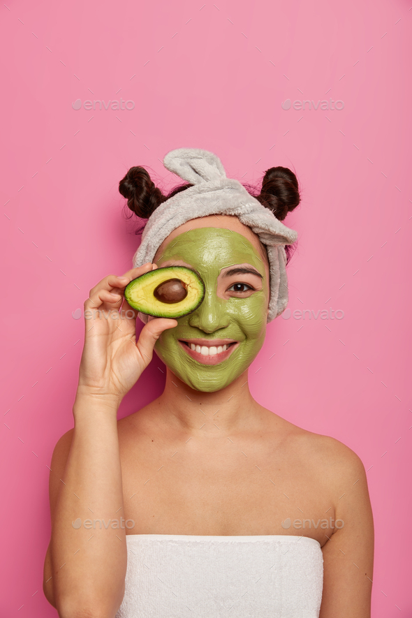 Beautiful happy Asian woman has pore cleaning procedure, applies green ...