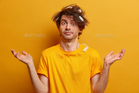 Horizontal shot of hesitant unaware man spreads palms sideways, shrugs ...