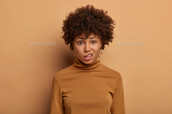 Puzzled African American woman has displeased expression, frowns face ...