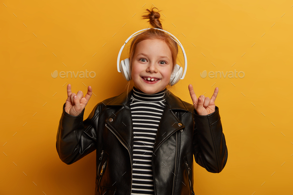 Optimistic kid rocker makes horn sign with fingers, enjoys listening ...
