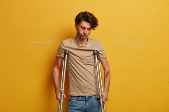 Sad unhappy man looks down, has serious injury after falling down from ...