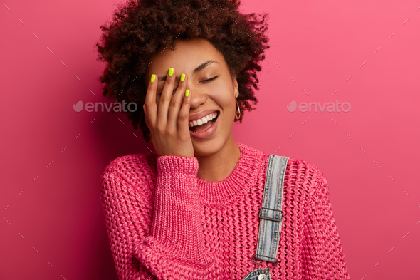 Carefree ethnic girl cannot stop laughing, keeps hand on face, has ...