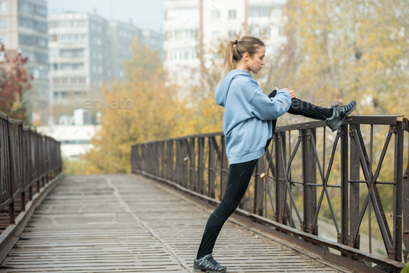 Girl standing on bridge with left leg bent in knee on fence and ...