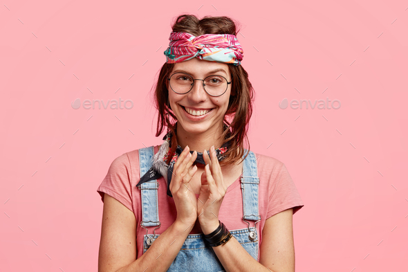 Happy female hippy makes intriguing gesture, looks with cunning ...