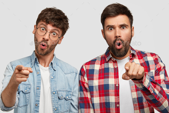 Surprised two guys point at camera, have shocked stunned expressions ...