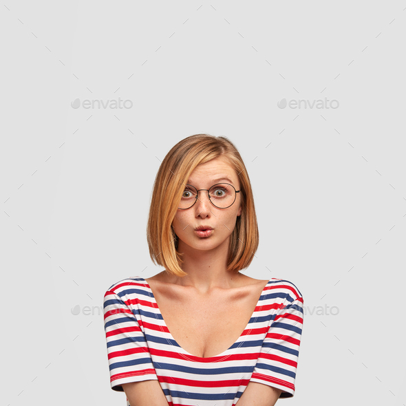 Vertical shot of amazed beautiful Caucasian female has stunned puzzled ...