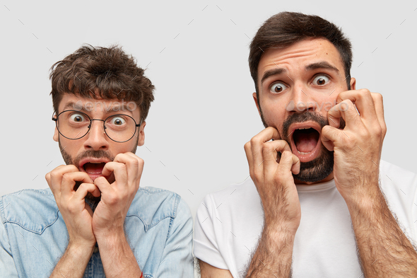 Frightened two men have scared expressions, look nervously, notice ...