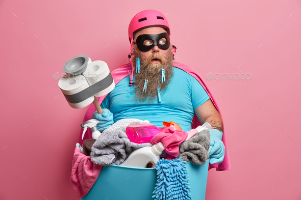 Shocked bearded plump man janitor in superhero costume looks after ...