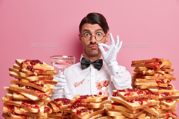 Professional waiter stands with glass of alcoholic cocktail, shows ...