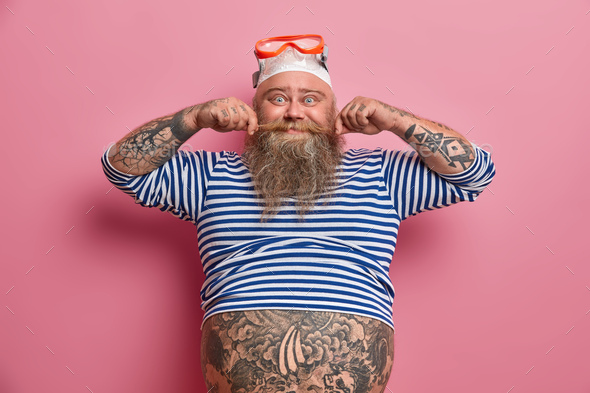 Joyful stout man curls mustache, has thick beard, cheerful face ...