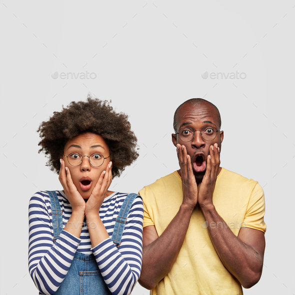 Vertical shot of stupefied African American male and female stare at ...