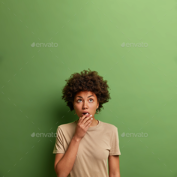 Scared Afro American teenage girl covers mouth, stares above with ...