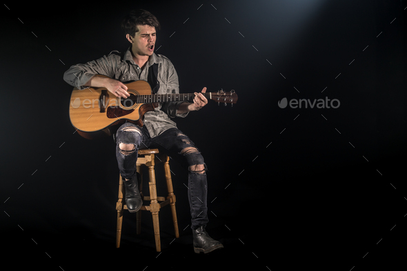 musician playing acoustic guitar, sitting on high chair, black ...