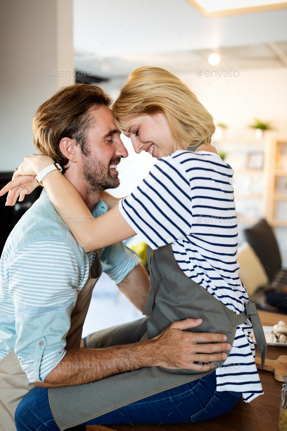 Spontaneous romantic couple making love in kitchen while preparing food ...