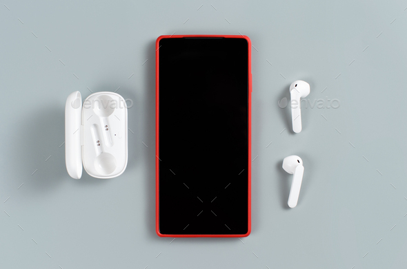Red Cell phone and white wireless earphones Stock Photo by katrinshine