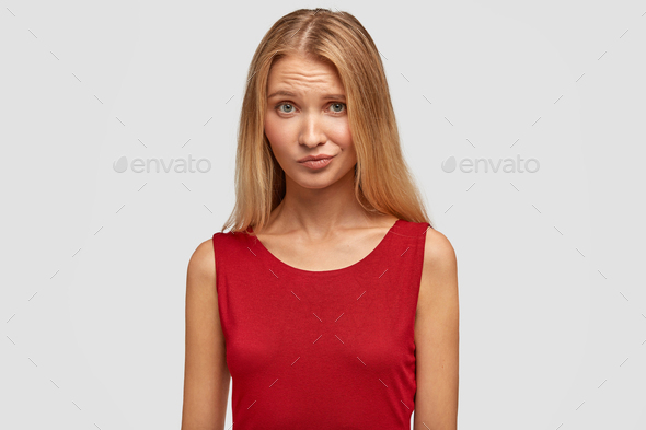 Waist up portrait of adorable female with hesitant facial expression ...