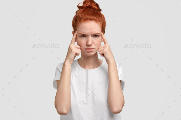 Studio shot of displeased ginger woman has gloomy facial expression ...