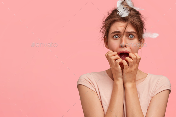Lovely scared female opens mouth, dressed in casual t shirt, stands ...