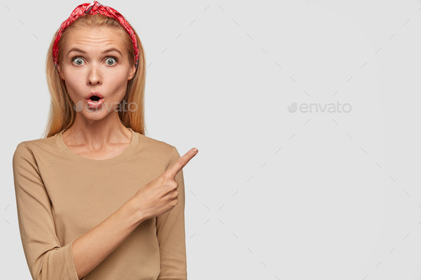 Image of surprised Caucasian woman with stupefied expression, points at ...