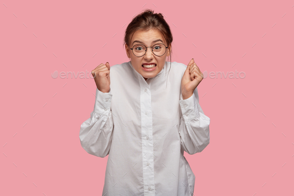 Emotional angry woman clenches fists with vexed expression, cant ...