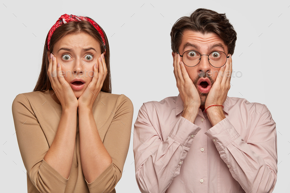 Shocked girlfriend and boyfriend gasp from fear, keep hands on cheeks ...
