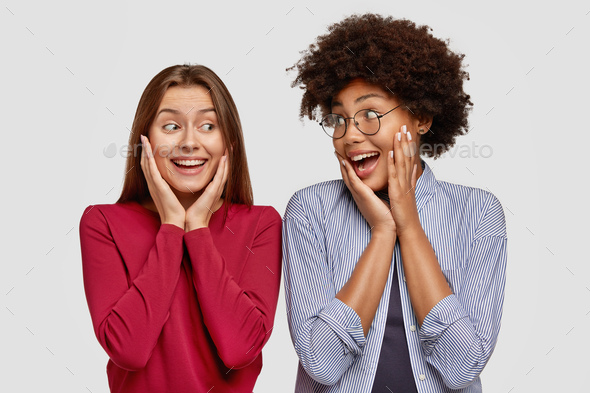 Positive girls of different races, keep hands on cheeks, being in high ...