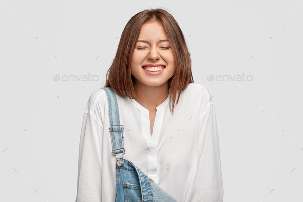 Pleased attractive female with overjoyed expression, keeps eyes closed ...
