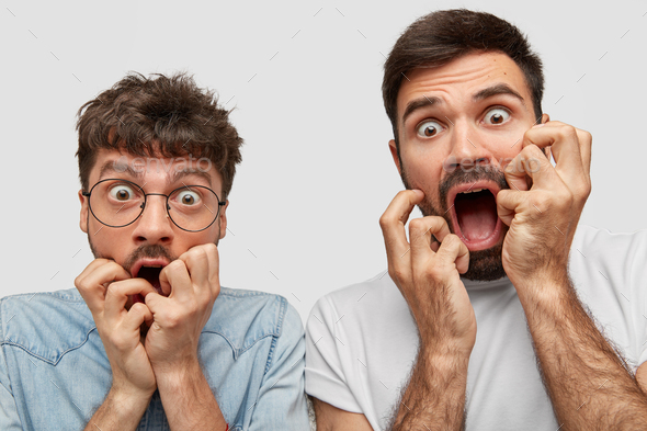 Close up shot of emotive stupefied men stare at camera with bugged eyes ...