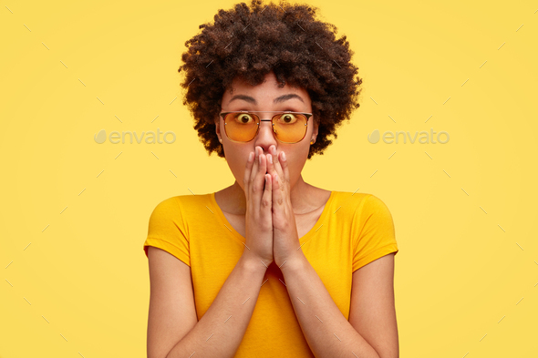 Emotional surprised dark skinned woman with stunned expression, covers ...