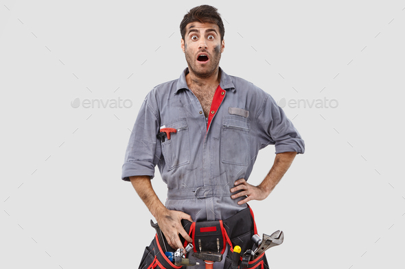 Disturbed surprised craftsman wears tool belt and overalls, reacts on ...