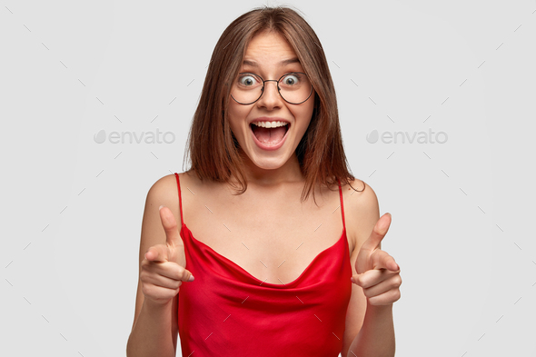 Hey, you! Joyful pretty female model has overjoyed expression, smiles ...