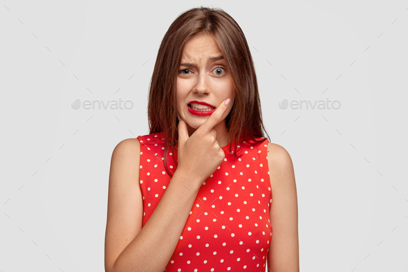 Troublesome puzzled Caucasian woman frowns face, clenches teeth, raises ...