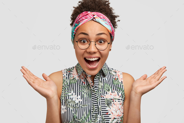 Overjoyed happy dark skinned young attractive female raises palms, has ...