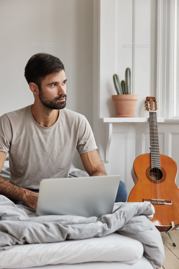 Pensive male writer works on laptop computer, creates new masterpiece ...