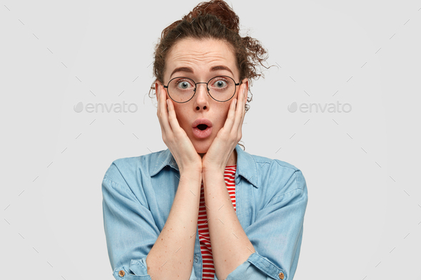 Stunned European girl has stupefied expression, opens mouth, keeps both ...