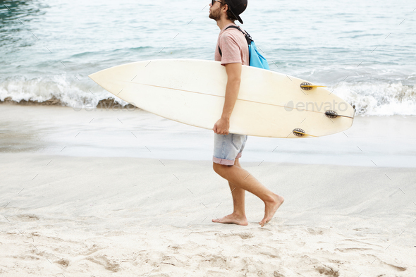 Side view of fashionable young Caucasian surfer wearing sunglasses and ...
