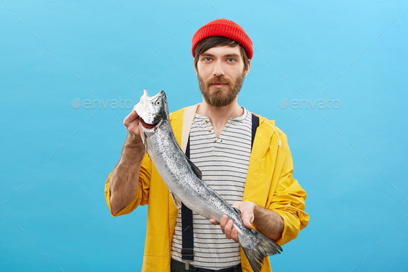 Portrait of bearded fisherman dressed casually standing with huge fish ...
