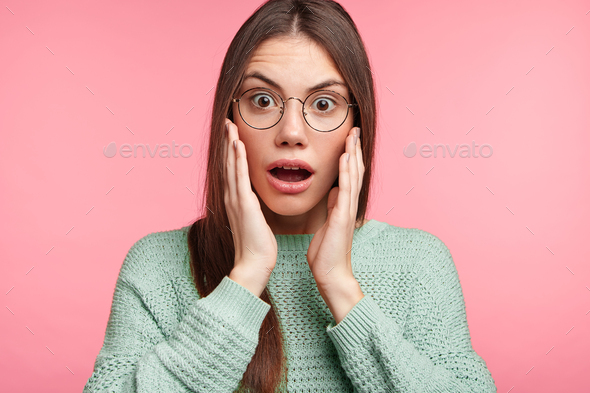 Indoor shot of scared female looks with bugged eyes and opened mouth ...