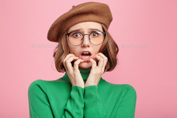 Scared worried pretty female model looks in terror at camera, realizes ...