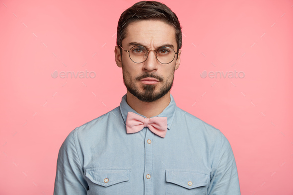 Serious strict male boss has trendy hairdo, wears formal shirt with bow ...
