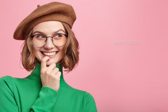 Joyful female with intriguing and curious expression, looks aside as ...