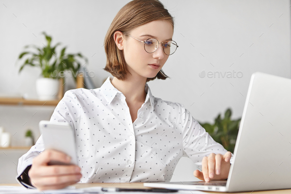 Serious hard working pleasant looking smart female banker uses modern ...