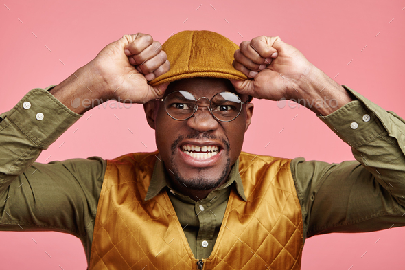 Portrait of angry dark skinned man has regretful look, keeps hand on ...