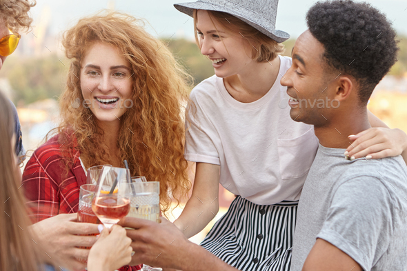 Group of mixed race friends raising drinks for cheers celebration ...