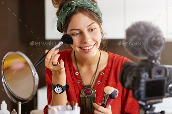 Camera taking photo of woman putting make up on her face, using ...