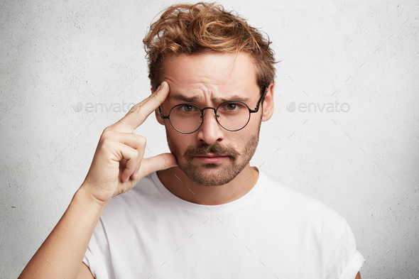 Handsome serious young male professor dressed casually, looks through ...