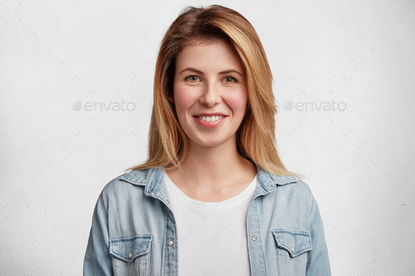 Happy pleased female model with glad smile, dressed in denim shirt ...