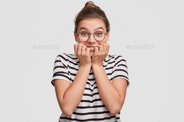 Portrait of cheerful young female giggles, clenches teeth and smiles ...