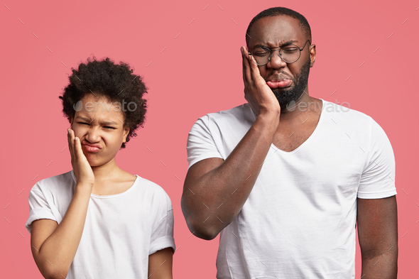 Dark skinned young man and little kid have unhappy sorrowful expression ...