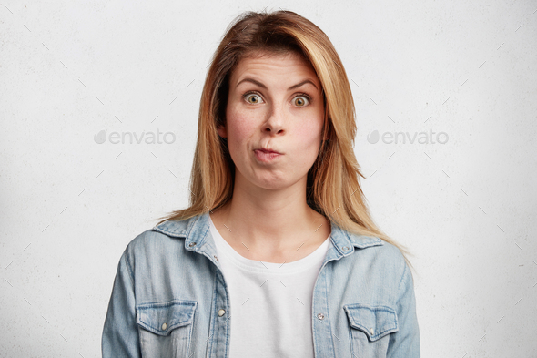 Puzzled female has hesitant expression, curves lips in doubt, can`t ...